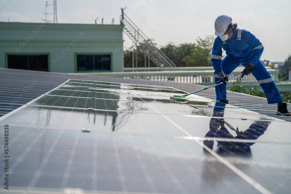 Man using a mop and water to clean the solar panels that are dirty with ...