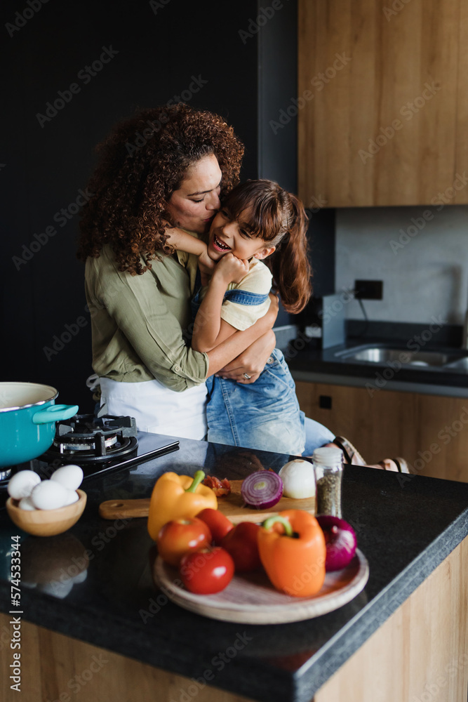 Hispanic mother and child daughter having fun while cooking at kitchen ...