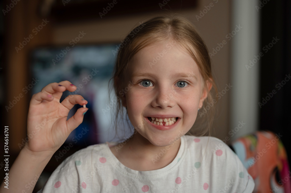 The little girl has just pulled her baby tooth and is waiting for the ...