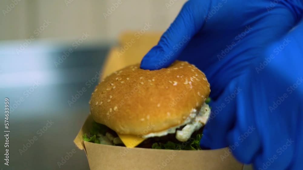 Chef is placing the delicious hamburger inside of the cardboard ...