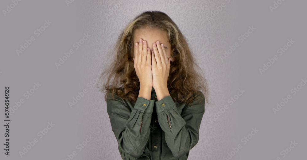Frightened teenage girl covers her face with her hands. The concept of ...