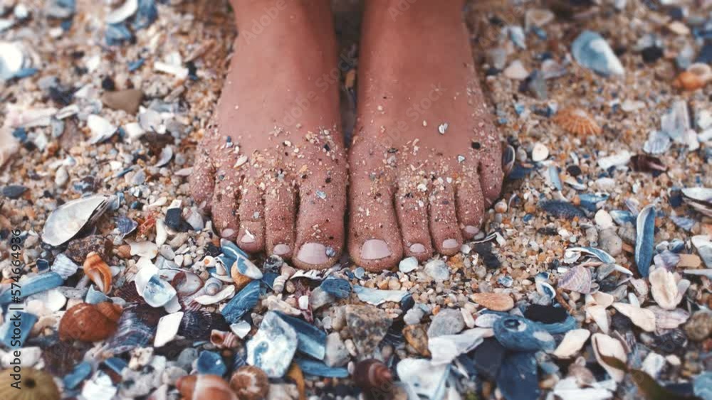 Woman feet in sand with sea shell on the beach during summer vacation ...
