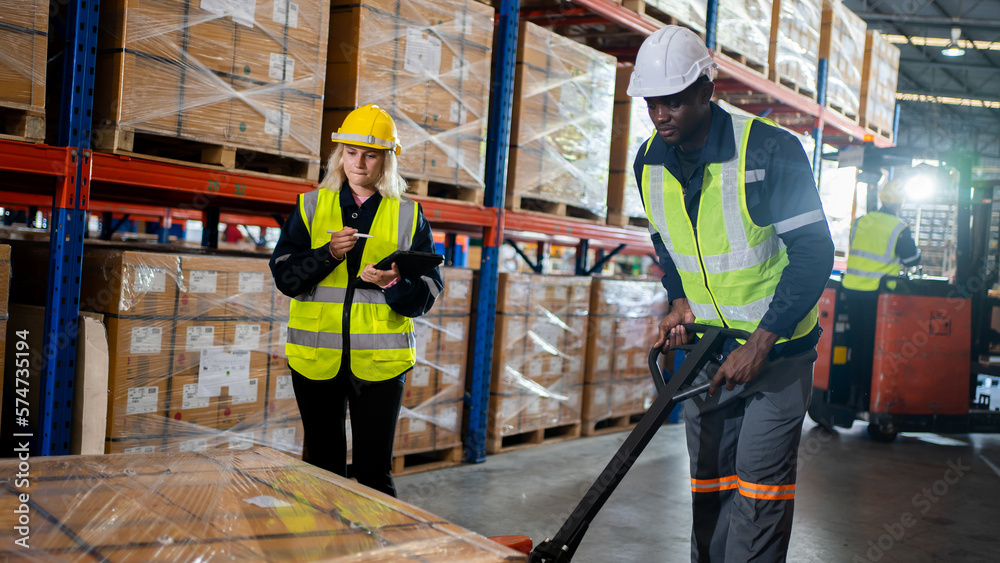 Fotka „Warehouse workers team pulling a pallet truck and checking stock ...