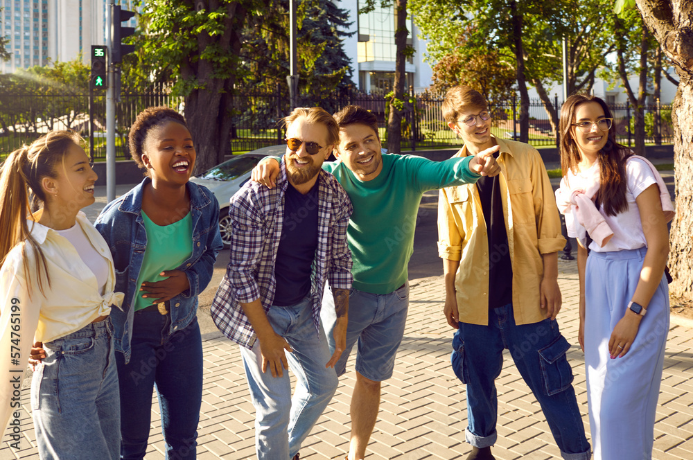 Group of cheerful tourist friends are walking together on streets of ...