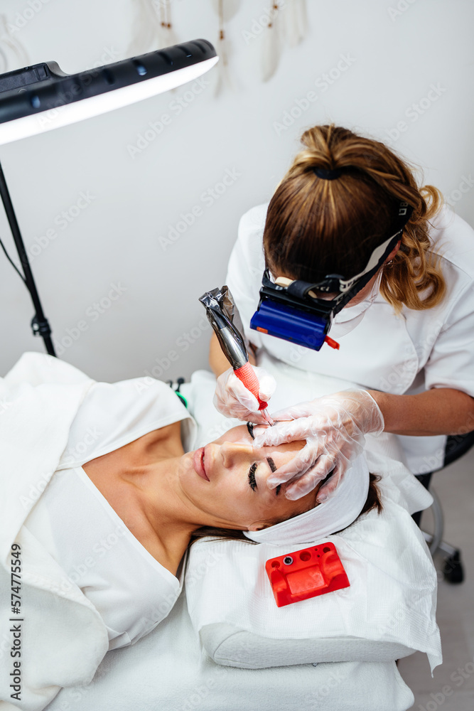 Beautiful young adult woman receiving professional permanent makeup ...