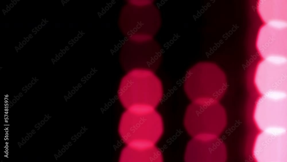 Vertically falling red blur dots. Red bokeh with reflexes fall down on ...