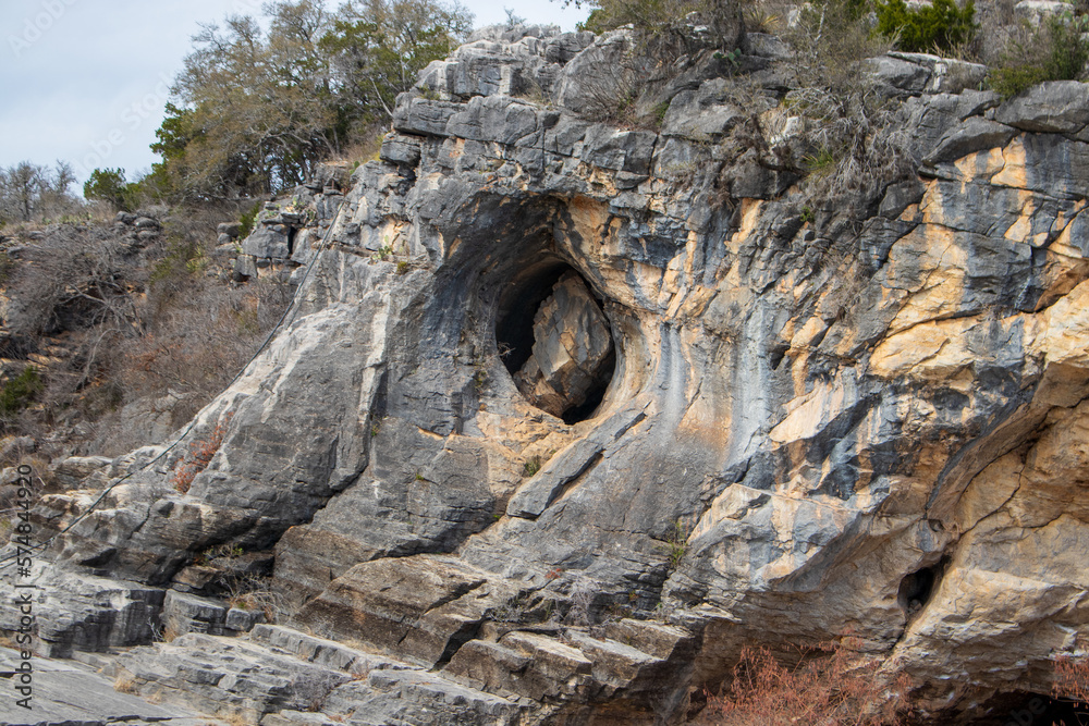 A wall of geological limestone formations creates a hole with a boulder ...
