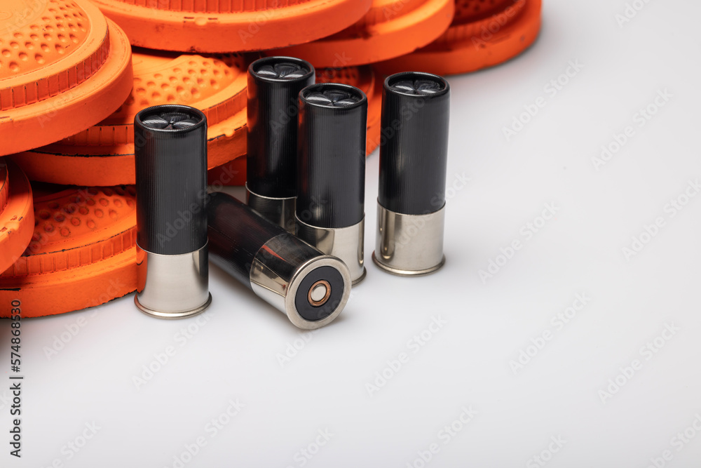Black shotgun shell bullets with clay shooting target on white ...