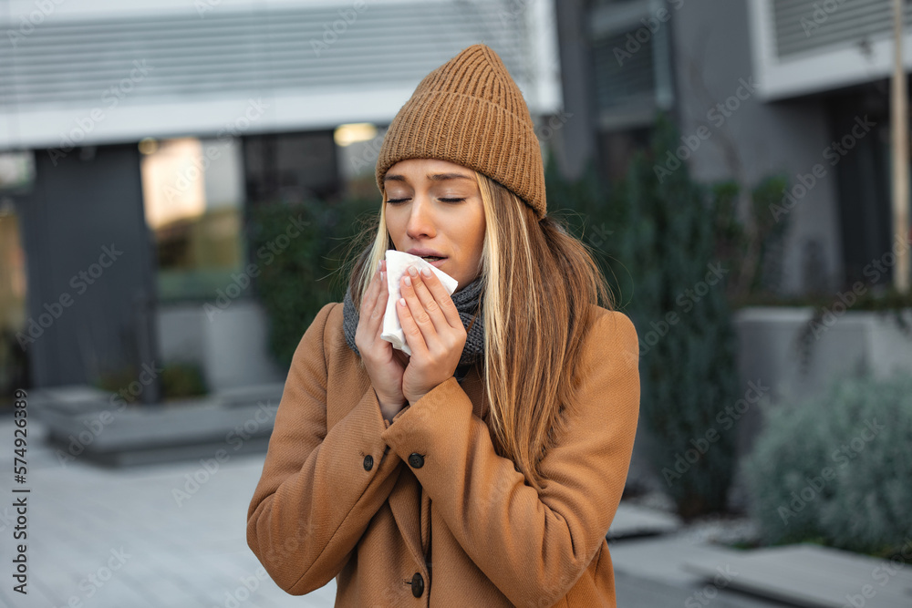 ill beautiful young woman sneezing and blowing nose in napkin. Sick ...