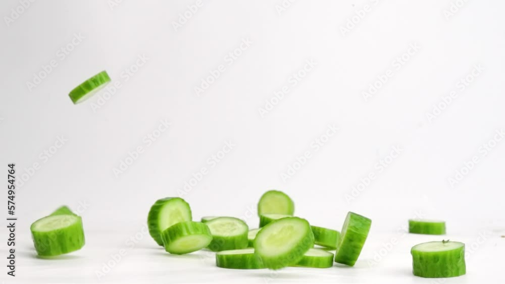 Persian mini cucumber slices falling onto white table top and bouncing ...