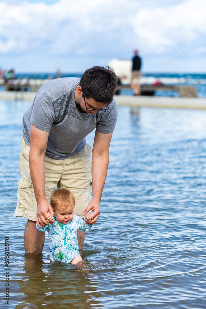 Happy child with dad in sea water in ocean pool at first trip to the ...