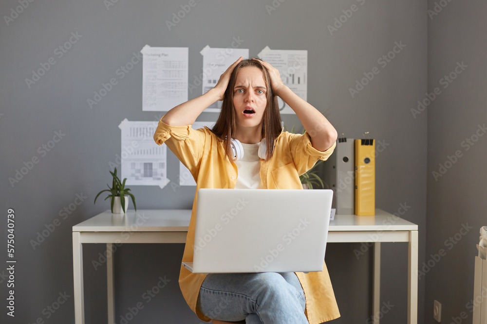Portrait of shocked scared woman wearing yellow jacket sitting at ...