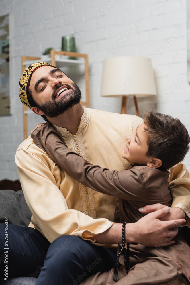 Smiling muslim child hugging father with prayer beads at home. Stock ...