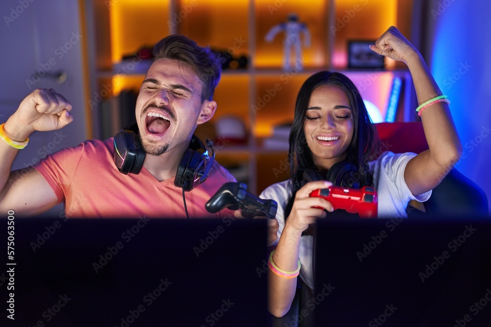 Man and woman streamers playing video game using computer and joystick ...