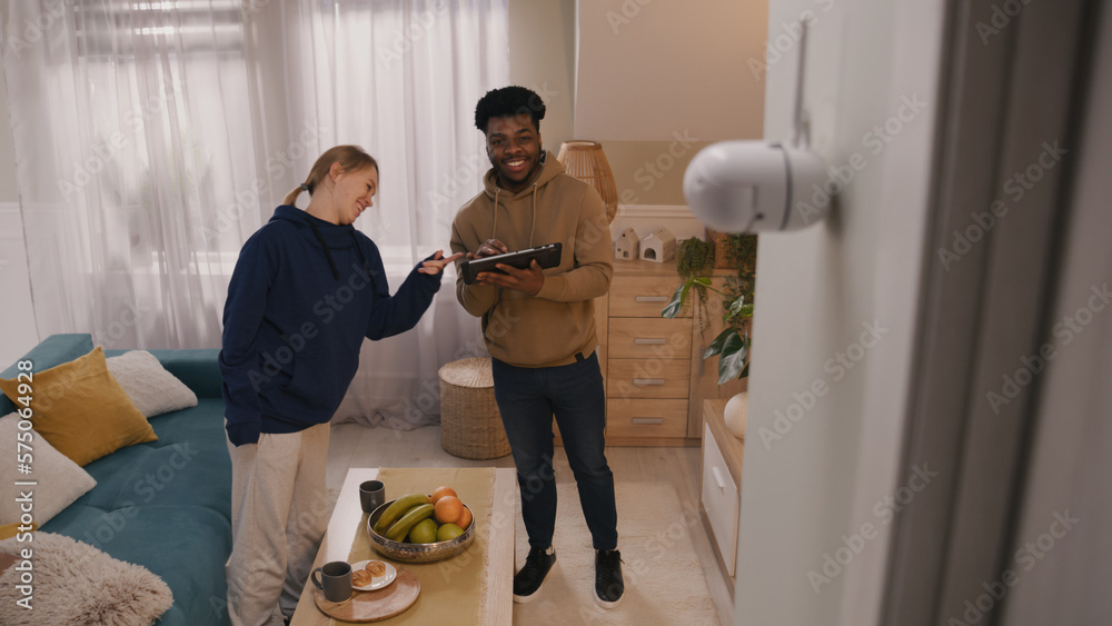 Foto de Multi ethnic couple install and set up security camera. Woman ...