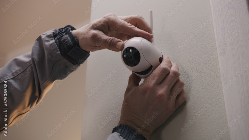 Foto de Installer in uniform puts security camera on wall fastening and ...