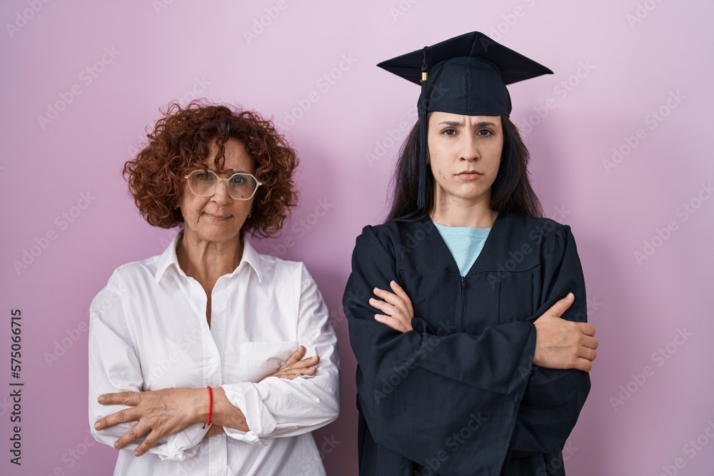 Hispanic mother and daughter wearing graduation cap and ceremony robe ...