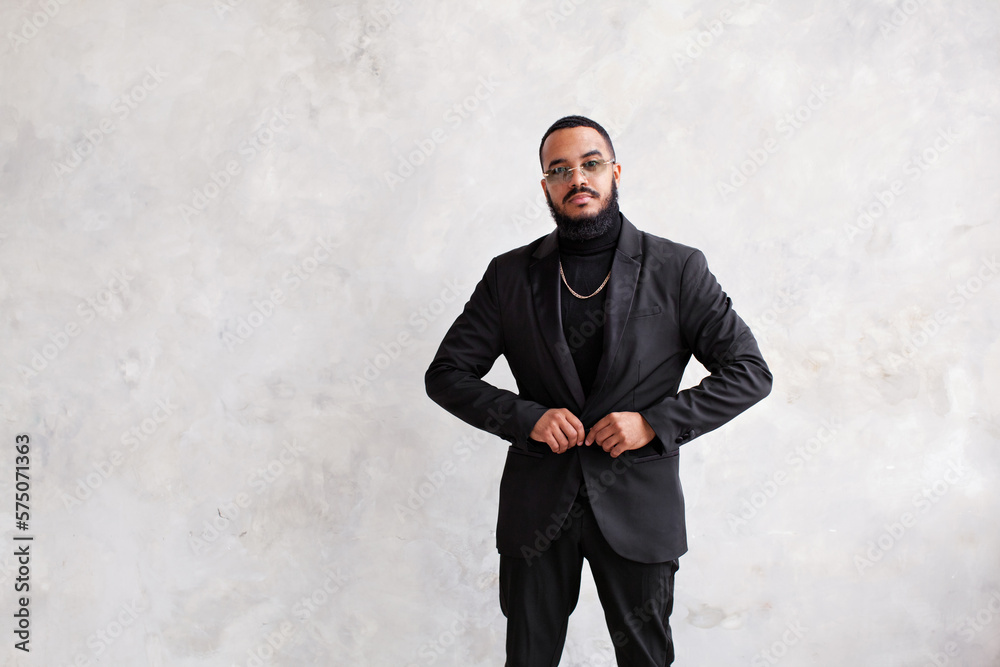 Handsome young arabian man with beard buttoning up jacket, wearing ...
