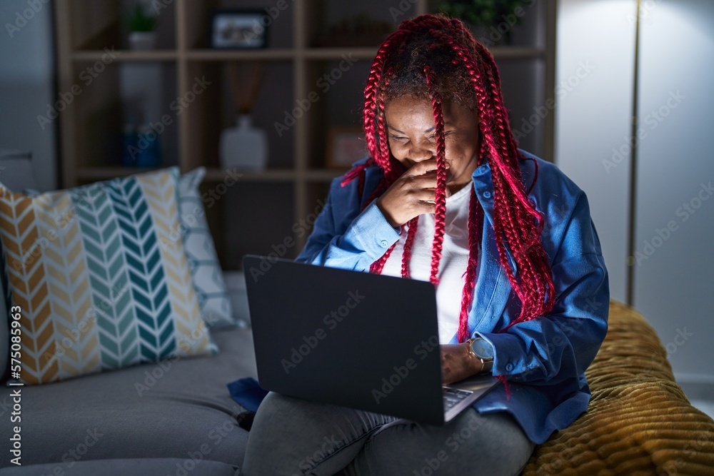 African american woman with braided hair using computer laptop at night ...