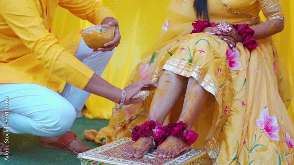 Turmeric is being applied to the bride's legs in India called as Haldi Ceremony. An Indian ...