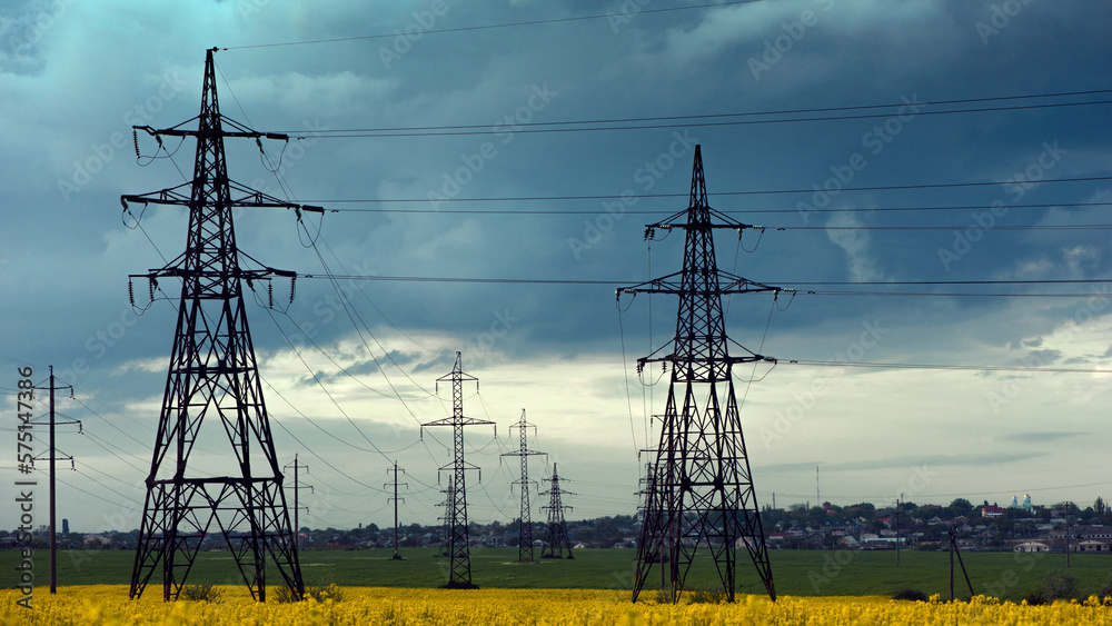 Rapeseed field and high voltage line. Power lines and sky with clouds ...
