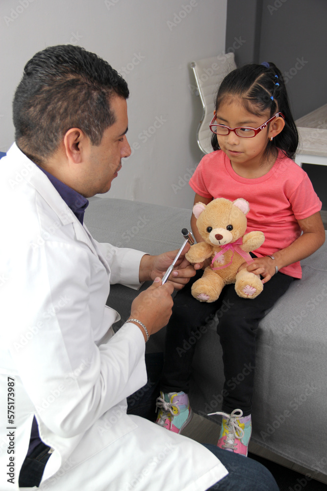 Latino pediatrician doctor checks his girl patient with autism spectrum ...