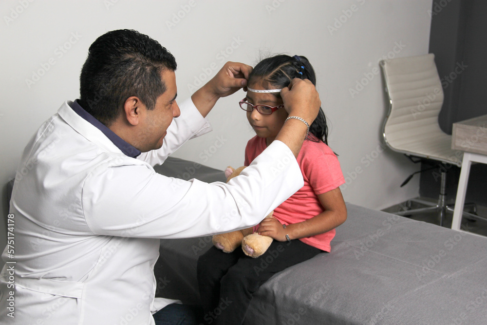 Latino pediatrician doctor checks his girl patient with autism spectrum ...