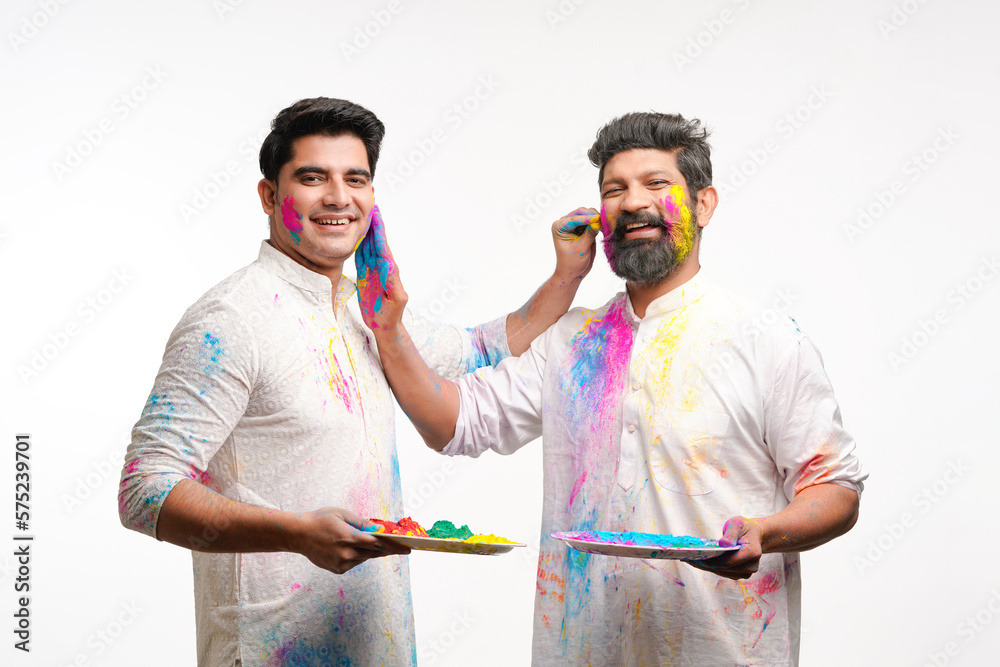Two indian man applying color to each other and celebrating holi ...