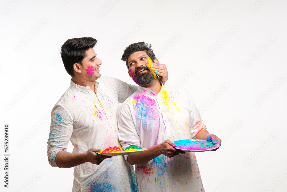 Two indian man applying color to each other and celebrating holi ...