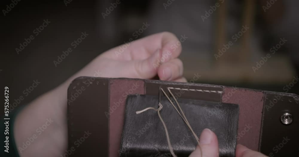 Close-up shot of leather sewing process. Hands with needle and strings ...