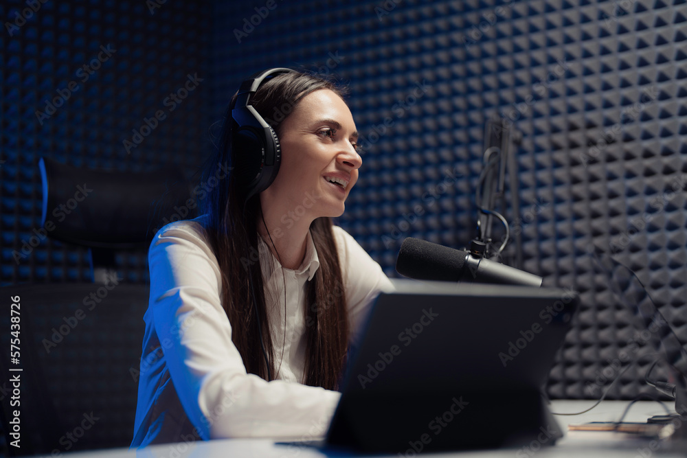 Young woman with headphones talking with guest during radio broadcast ...