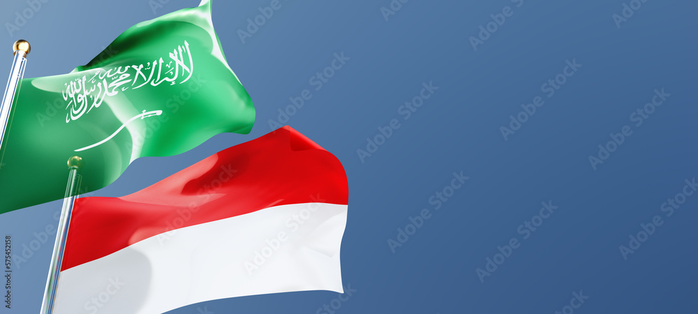 saudi arabia and indonesia flags waving in the wind against a blue sky ...