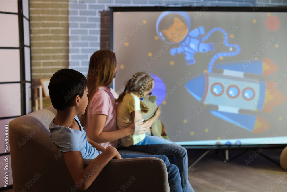 Little boy with his mother and sister watching cartoons on projector ...