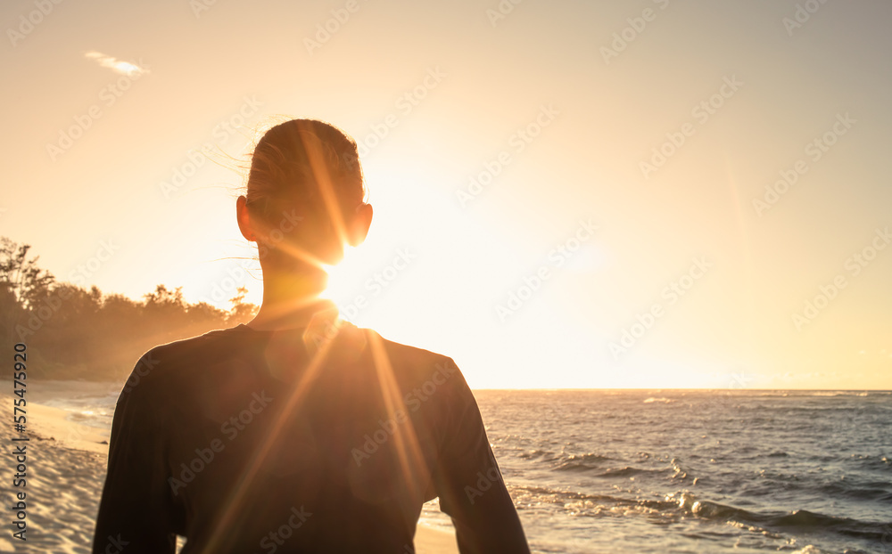 Thoughtful young woman looking out to the sunset feeling at peace in ...