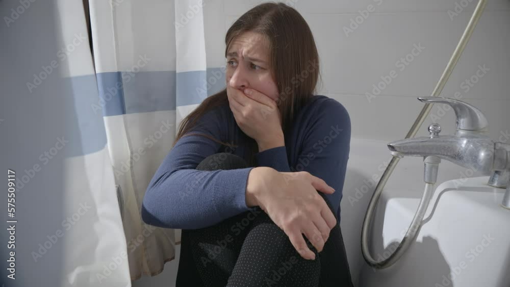 Young woman feeling scared hiding in bathroom and closing her mouth to ...