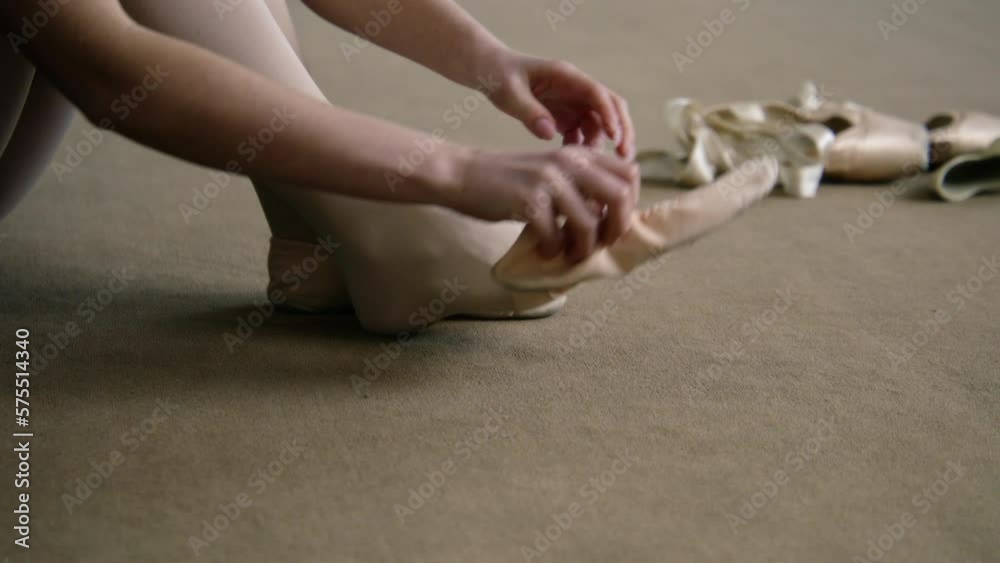 Beautiful ballet dancer sits on floor near pointe at dance studio and ...