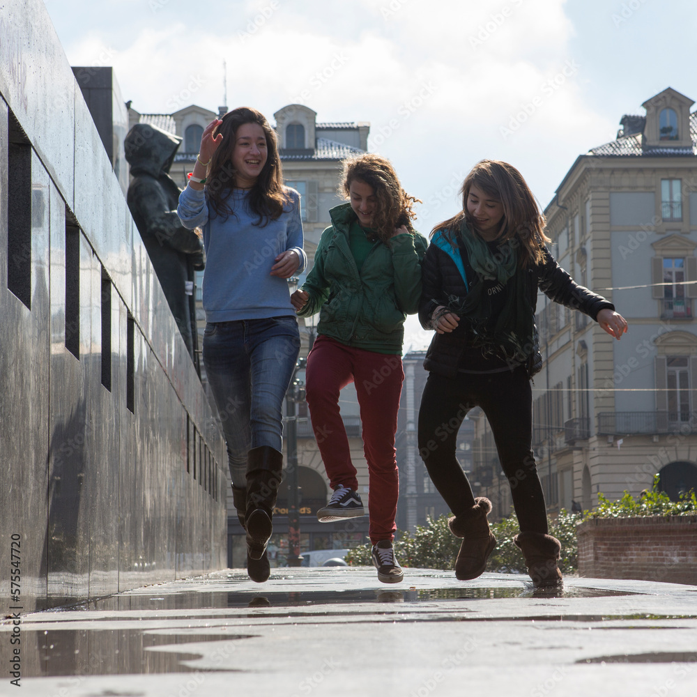 Teen girls splash through rain puddles in urban setting Stock Photo ...