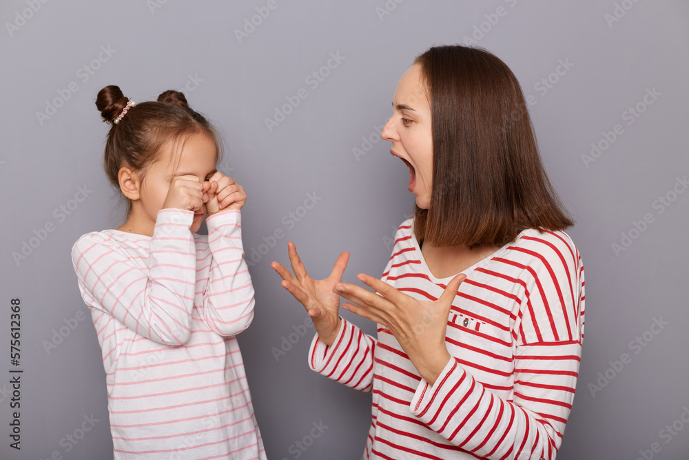 Indoor shot of aggressive angry woman and crying little girl with hair ...