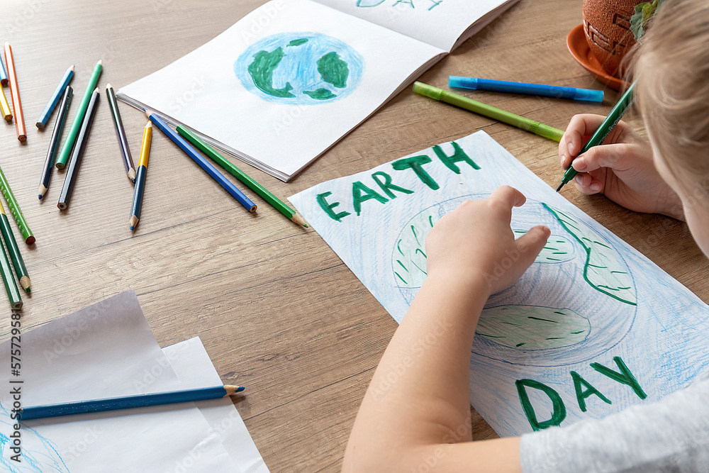 A child at home at the table draws the planet Earth with a world map ...