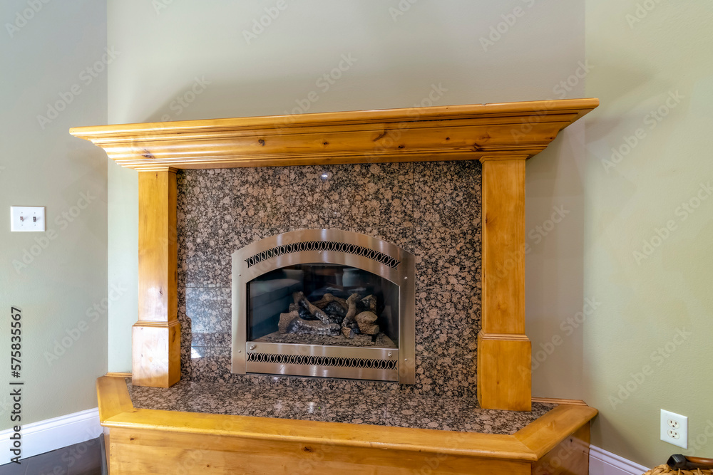 Fireplace with granite tiles surround and wood frame. Close-up of a ...