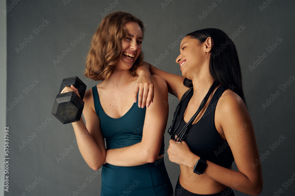 Young women in sports clothing laughing while face to face holding ...