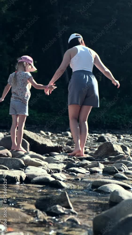 mother with daughter walking barefoot by rocks at mountain river vídeo ...