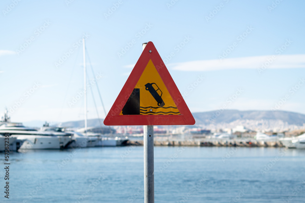 Triangular warning road sign, yellow with red outline depicting a car ...
