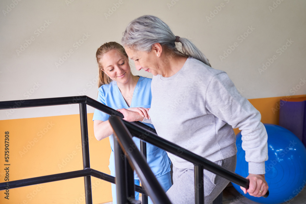 Caregiver assisting senior patient in movement therapy at nursing home ...