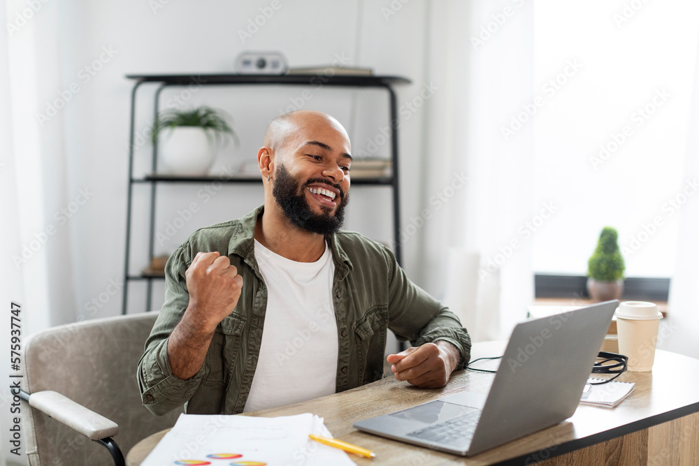 Great job. Happy latin man looking at laptop and expressing emotions of ...