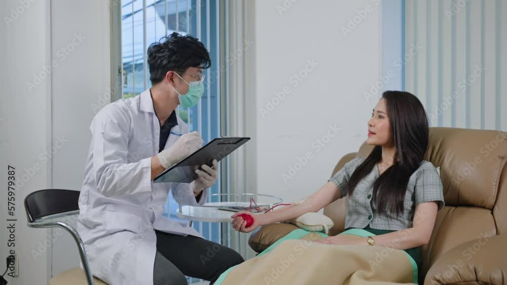 Young asian woman making blood donation and holding red ball with ...