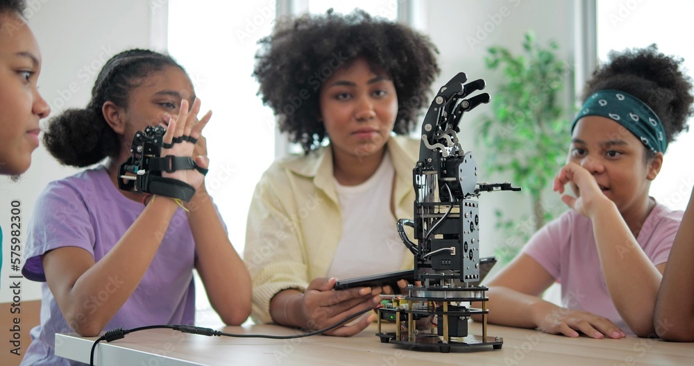 Group of African black teenager students learning about robotic arm ...