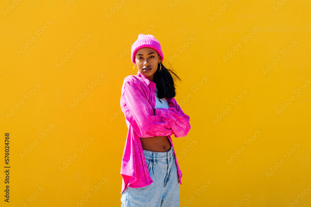 Confident hip hop dancer standing with arms crossed in front of wall ...