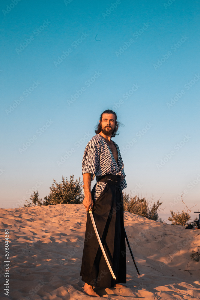 A Japanese warrior in a traditional kimano armed with a katana sword on ...