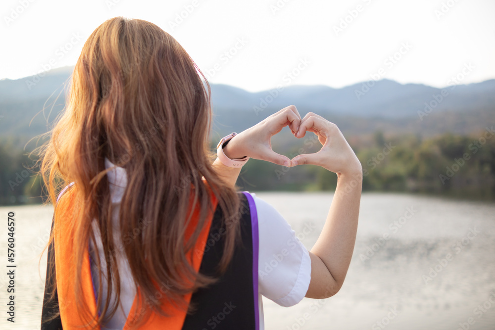 Young woman shows her hands up to form heart symbol to show friendship ...